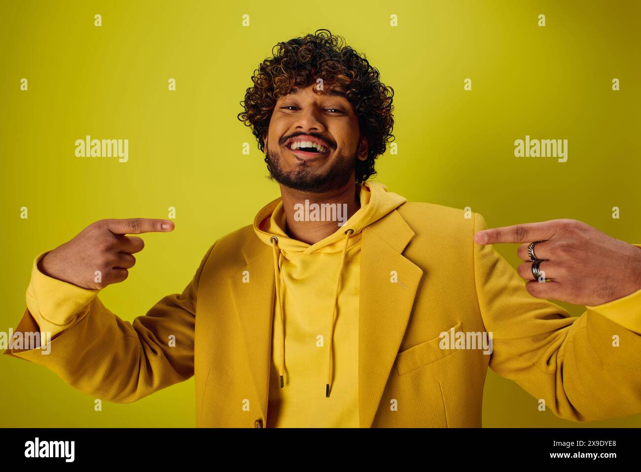 A handsome young Indian man in a yellow jacket pointing at something on ...