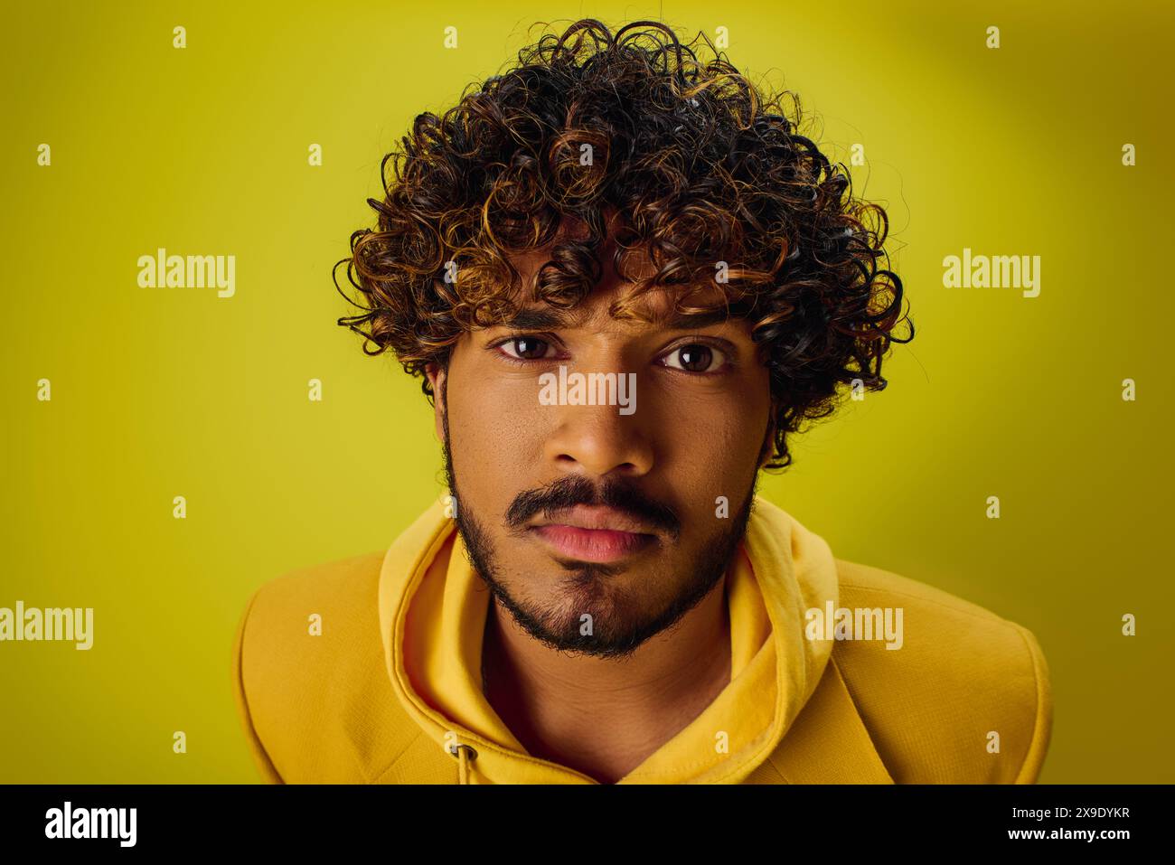 A young Indian man with curly hair strikes a pose in a yellow shirt ...
