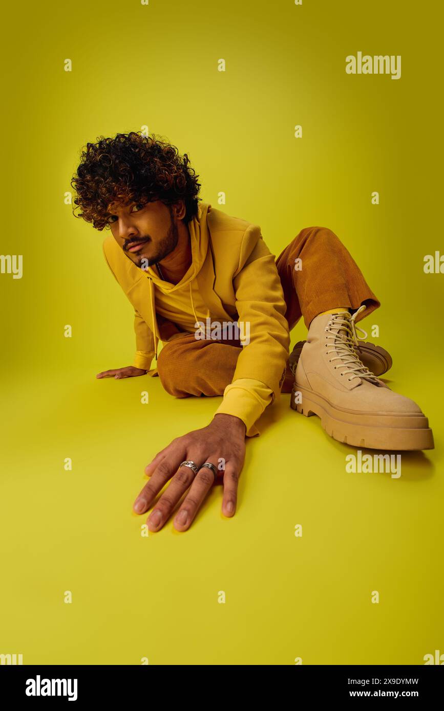 A man in vibrant attire sits gracefully with his hand touching the ...