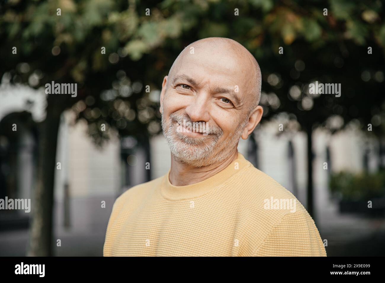 Senior Man in Yellow Sweater Smiling Gently in a Urban Setting Stock ...