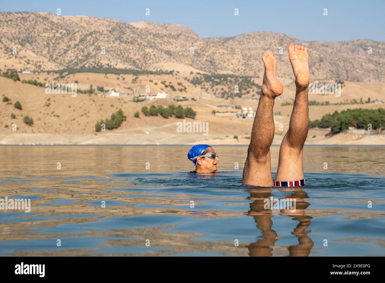 Swimmer handstand in lake, mountain backdrop in Kurdistan Stock Photo ...