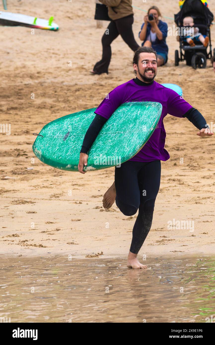 A happy laughing smiling surfer running to the sea during the Sand ...