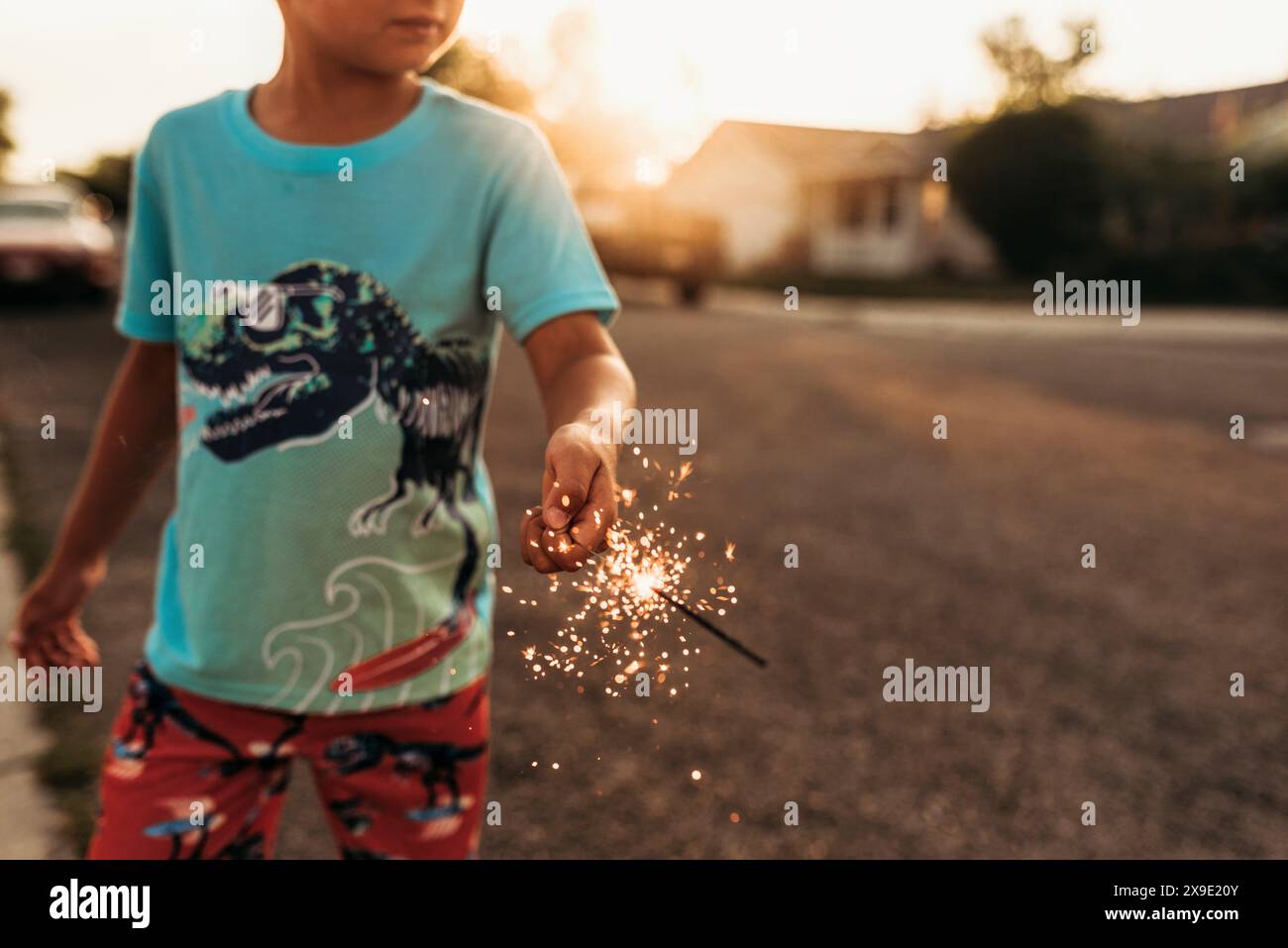 A boy enjoys a sparkler firework at sunset on a neighborhood road Stock ...