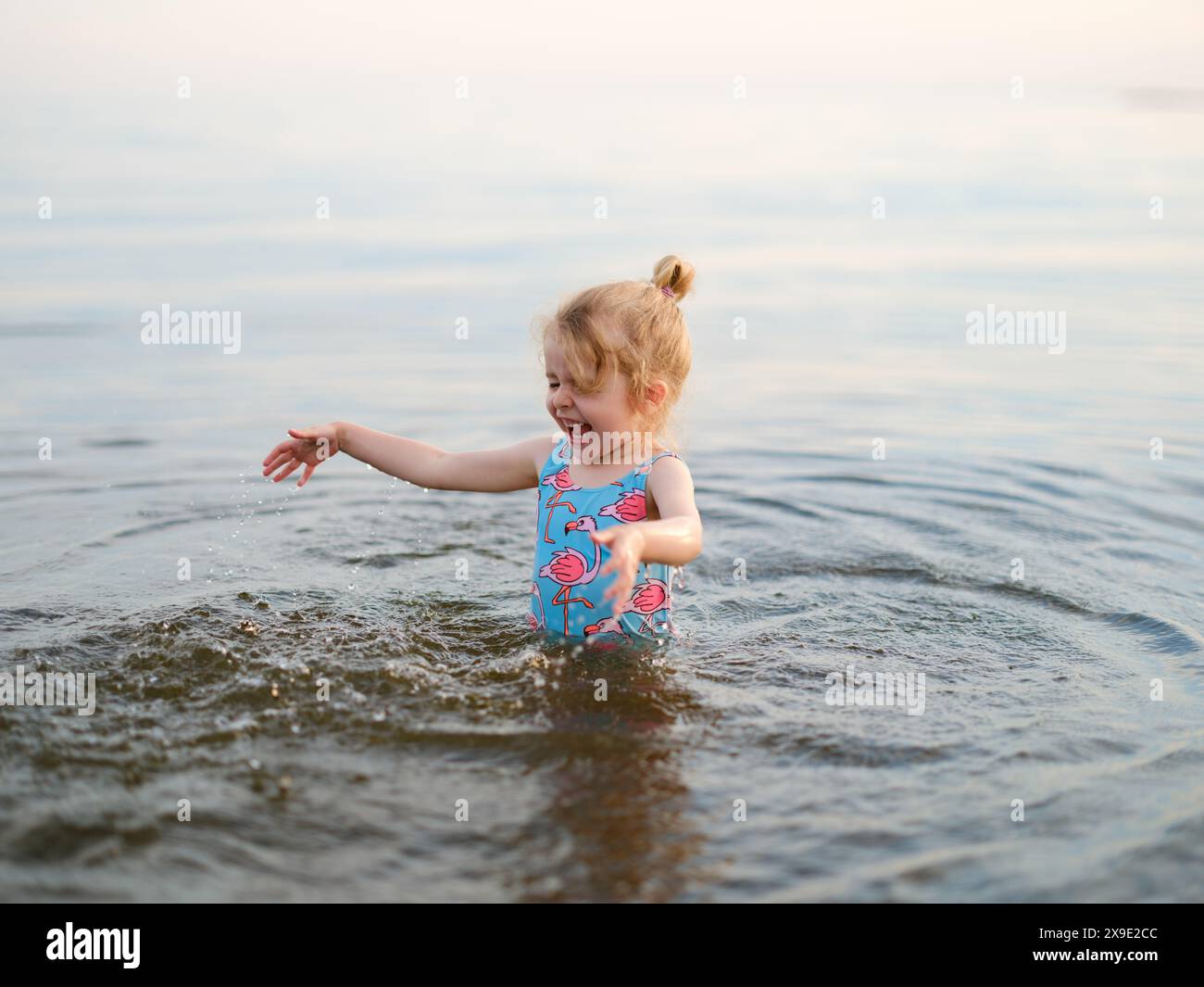Happy little girl child splashing in lake water Stock Photo - Alamy