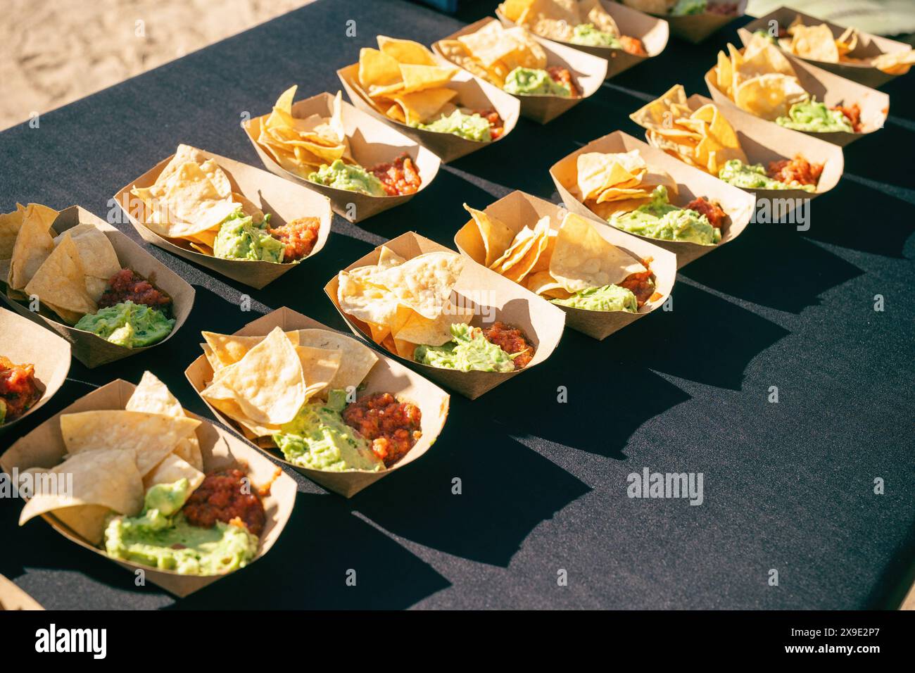 Chips, salsa and guacamole served in paper trays at an outdoor event ...