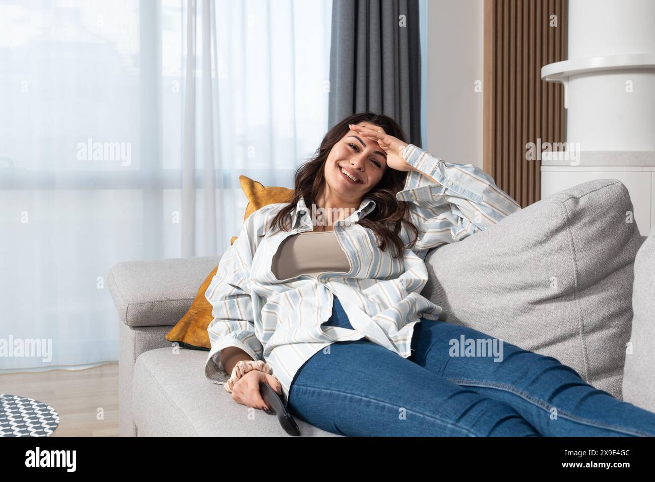 Laziness concept. Young lazy woman lying on the couch watching ...