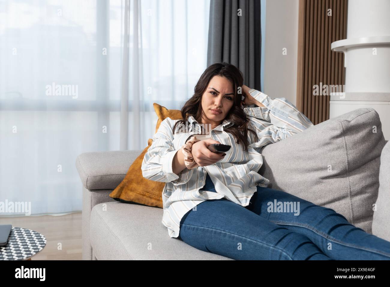 Laziness concept. Young lazy woman lying on the couch watching ...