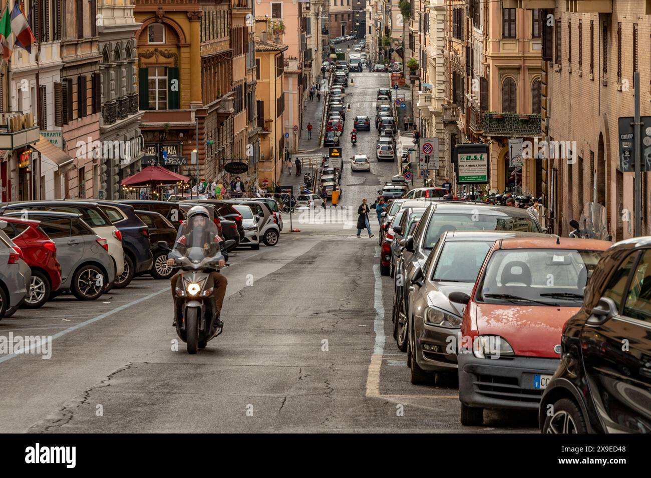 A man riding a motor scooter up a hill on Via di S. Maria Maggiore a ...