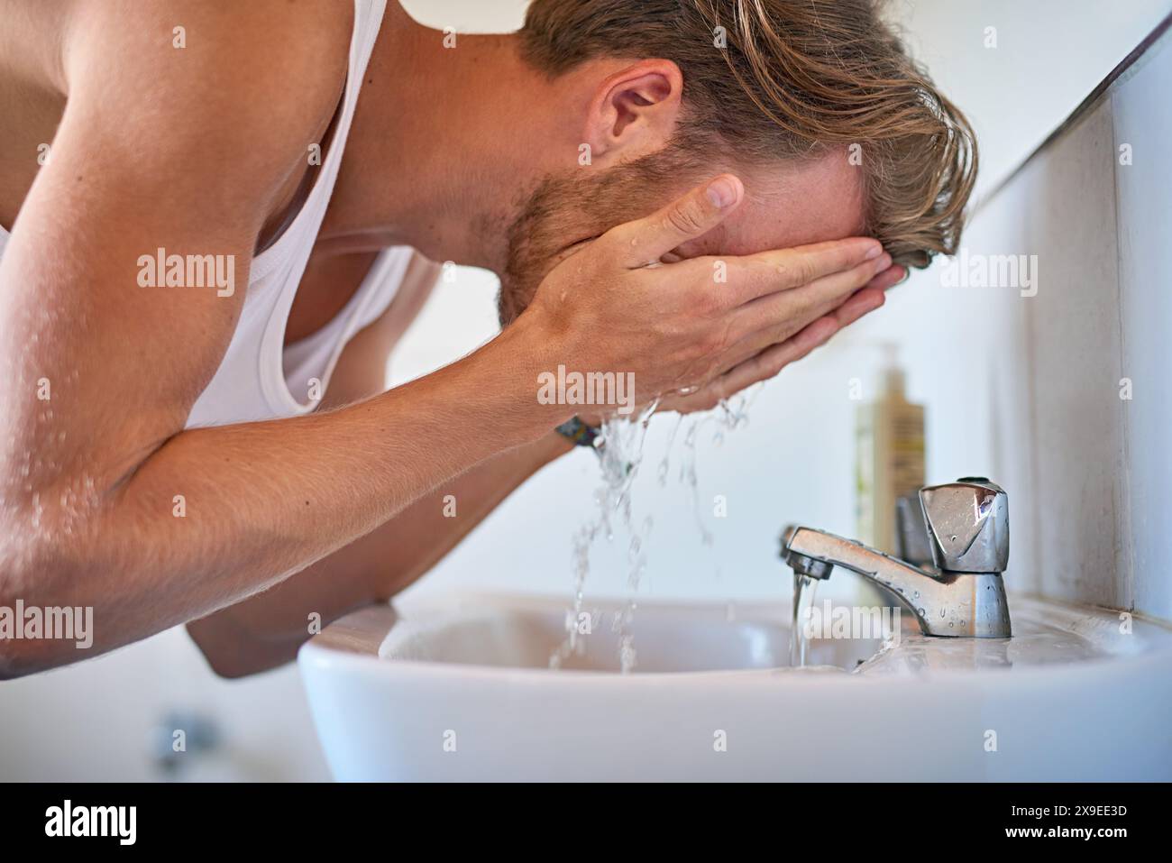 Water splash, skincare and hands of man in bathroom for washing face, hygiene or morning routine ...