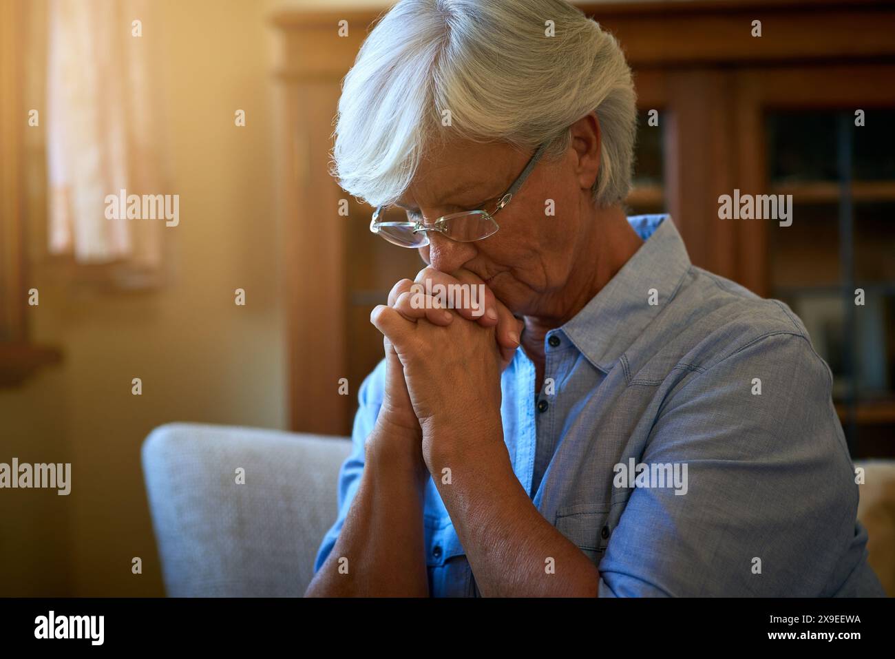 Worry, praying or senior woman with stress in with memory, trauma or fear on chair thinking ...