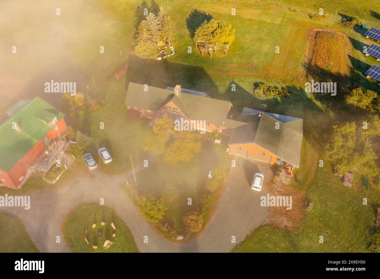 Farm with outbuildings in the autumn forest under the clouds. Drone top ...
