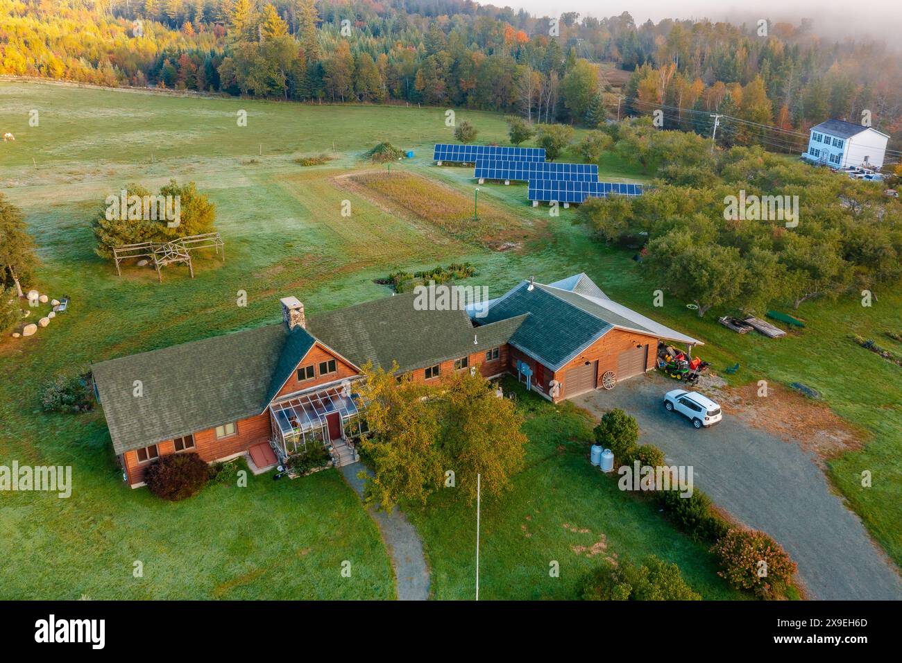 Farm with outbuildings in the autumn forest under the clouds. Drone top ...