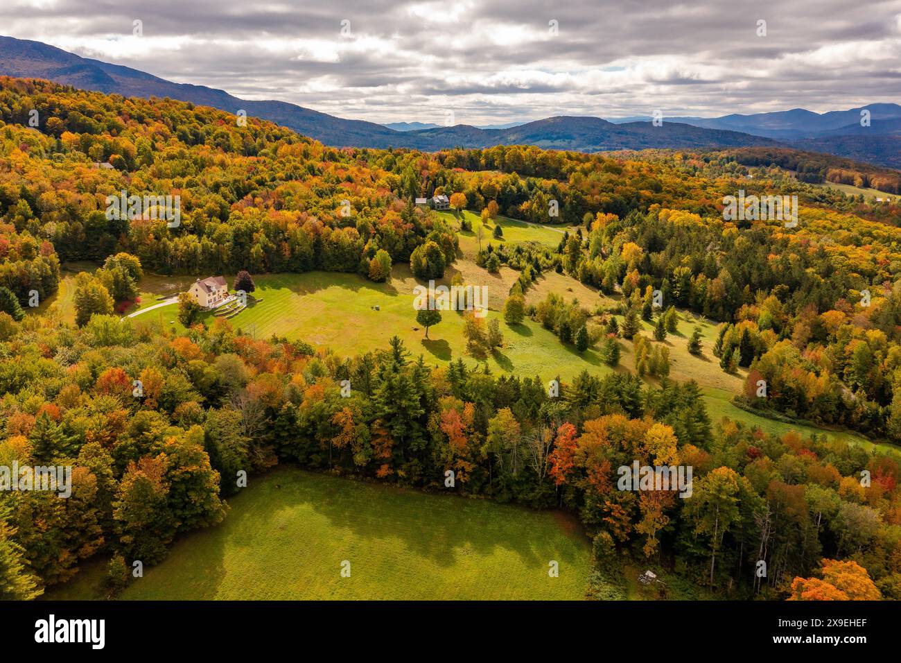 Autumn forest adorns isolated farmhouse under clouds, mountain backdrop ...