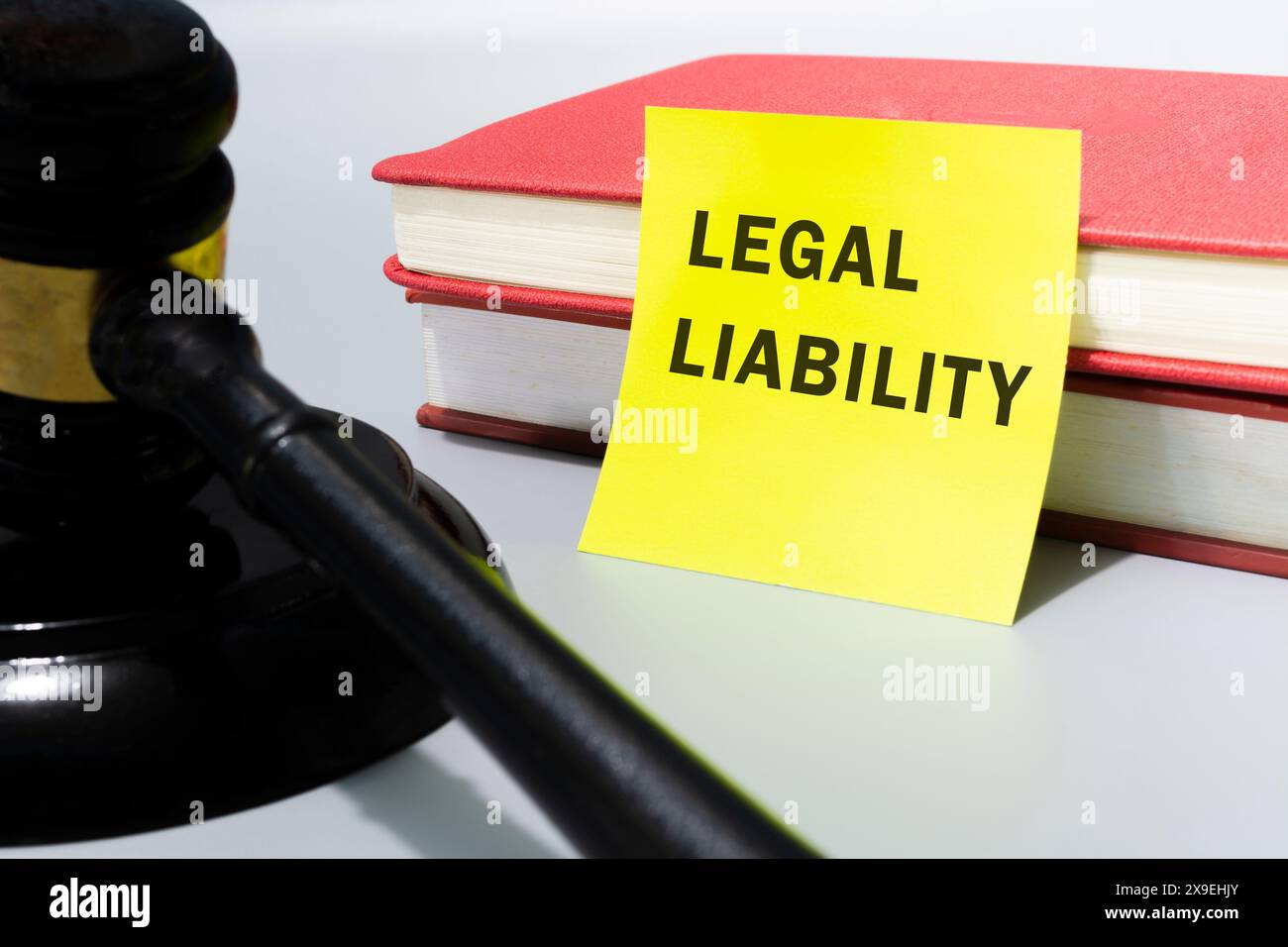 Judge's gavel with word legal liability written on yellow note and with ...
