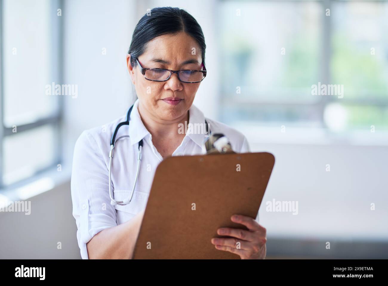 Focused Female Doctor Reviewing Patient Chart in Modern Hospital Stock ...