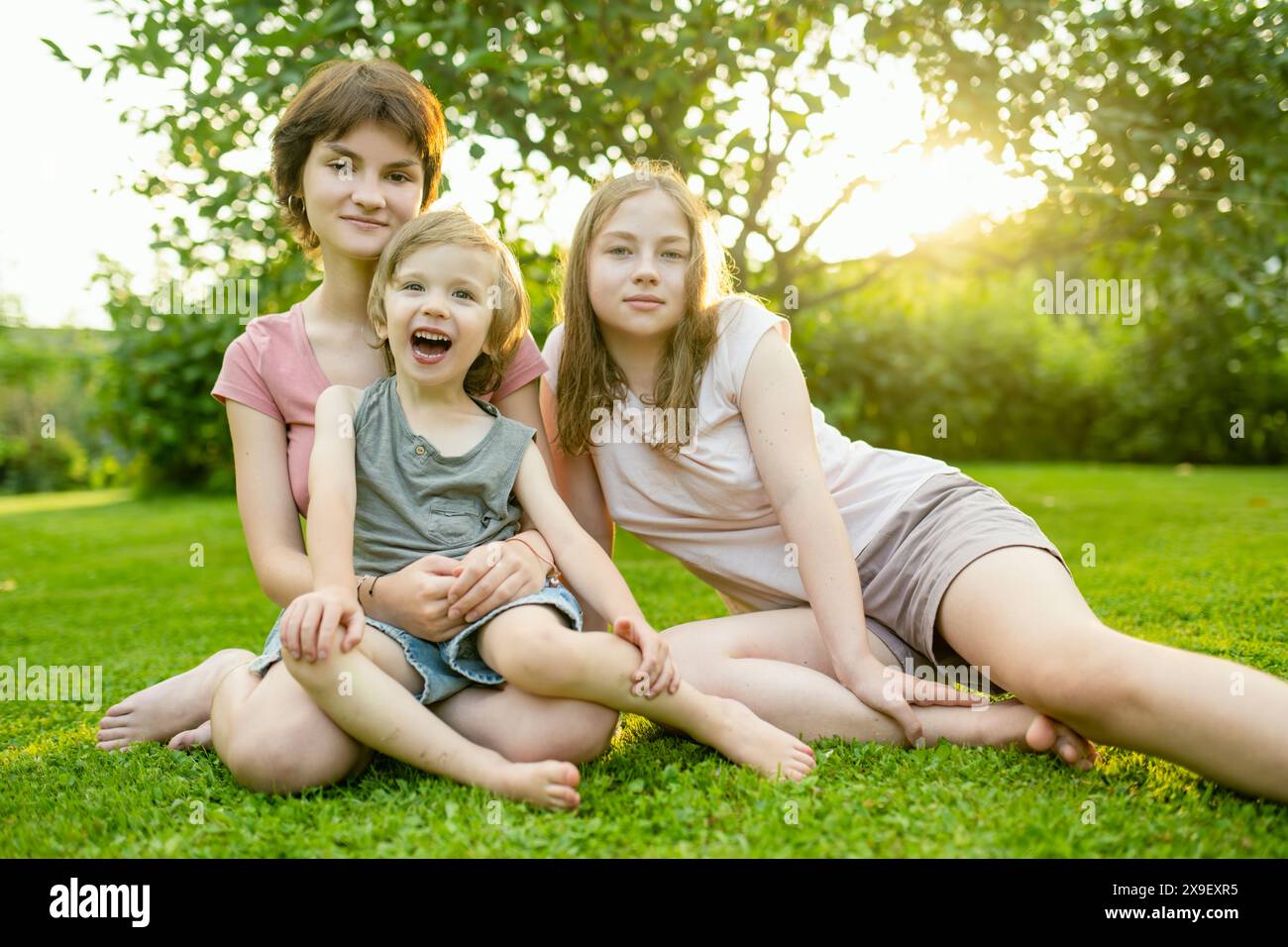 Cute big sisters cuddling with their toddler brother. Adorable teenage ...