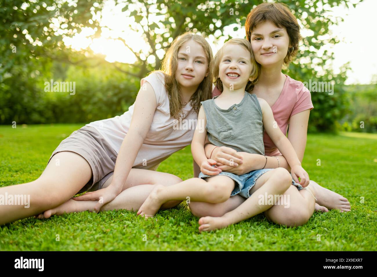 Cute big sisters cuddling with their toddler brother. Adorable teenage ...