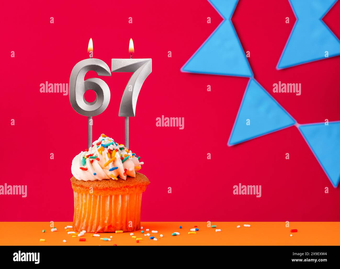 Number 67 candle with birthday cupcake on a red background with blue ...