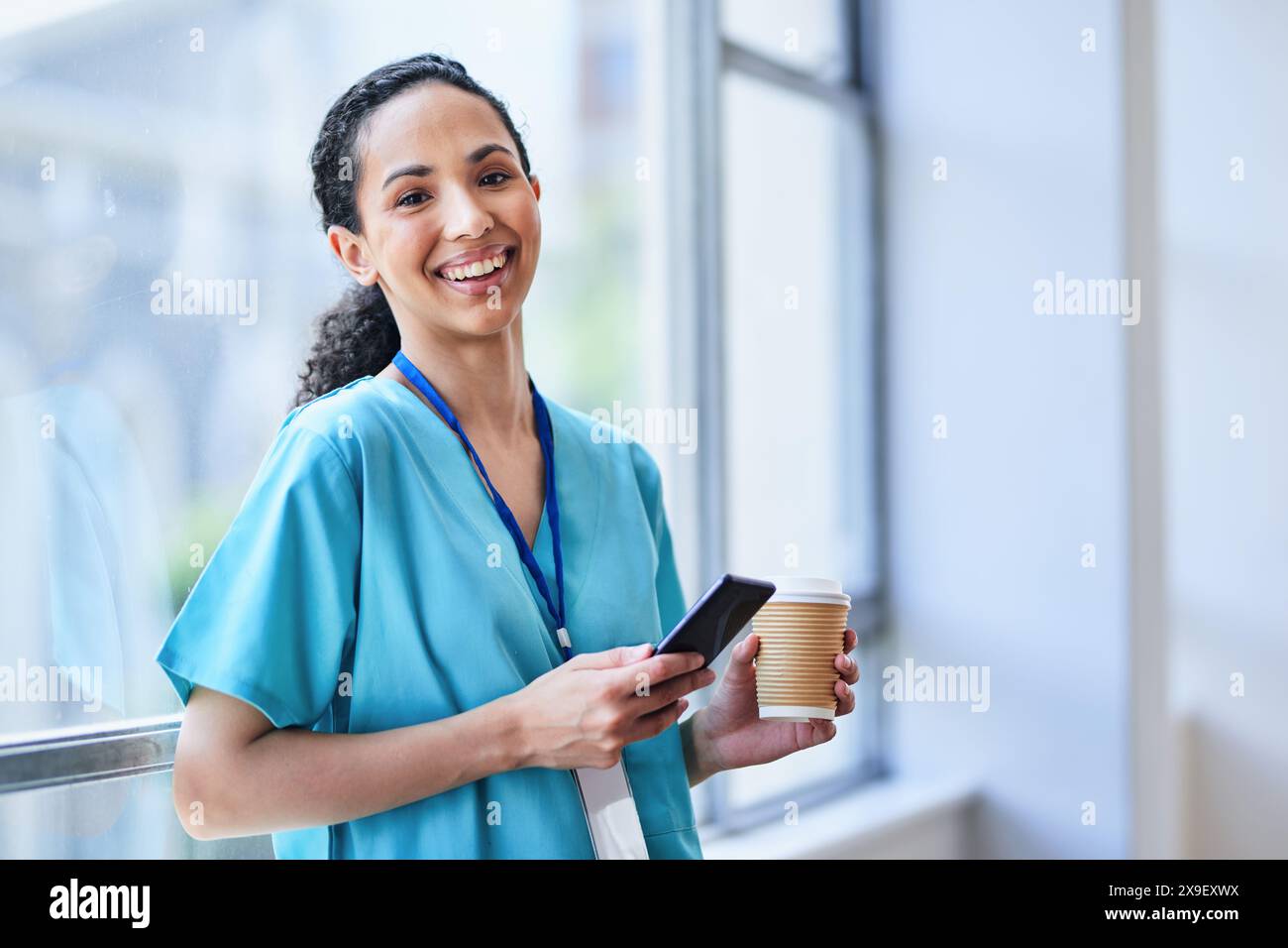Smiling Nurse Taking a Break with Coffee and Smartphone in Hospital ...
