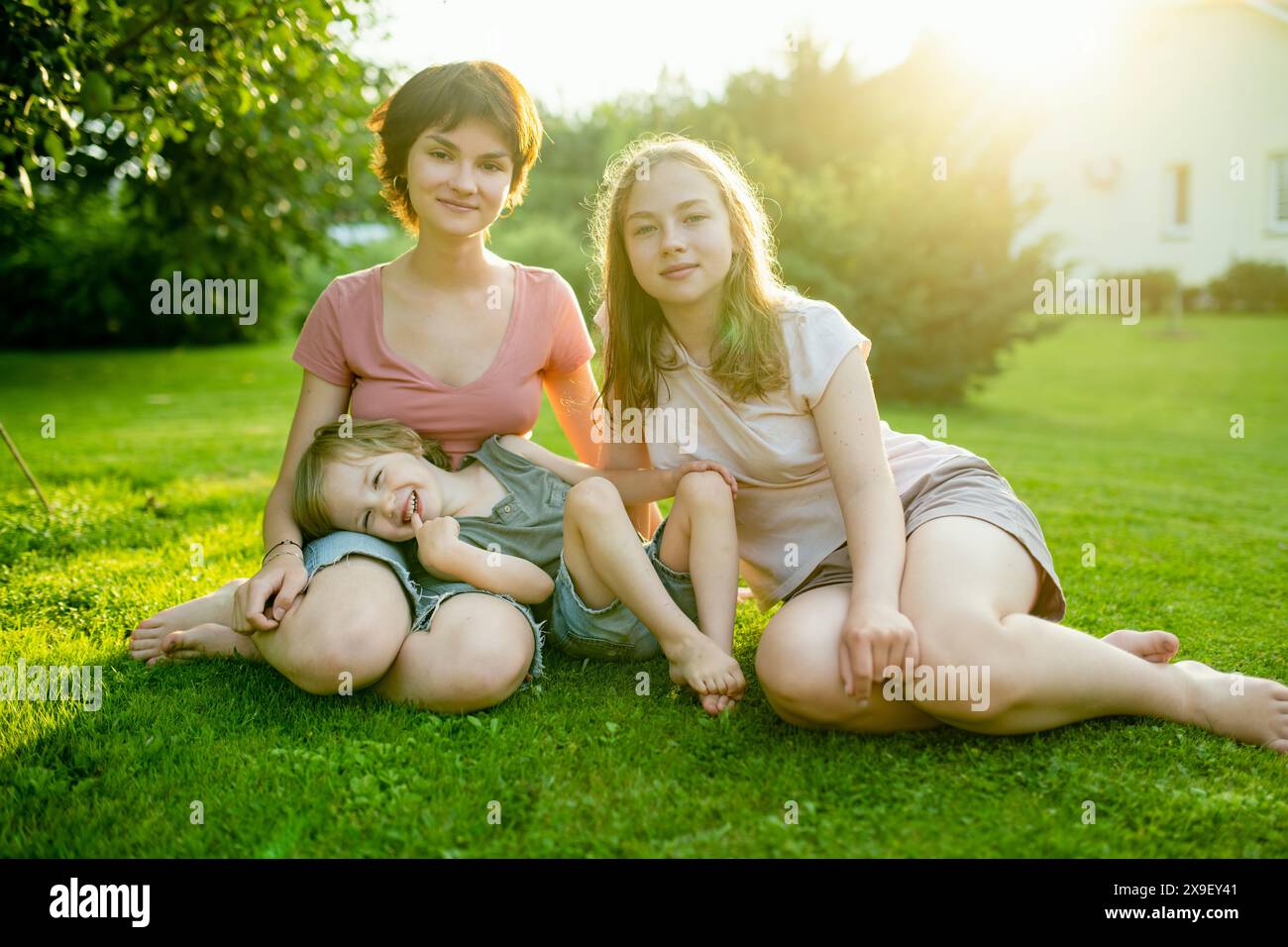 Cute big sisters cuddling with their toddler brother. Adorable teenage ...