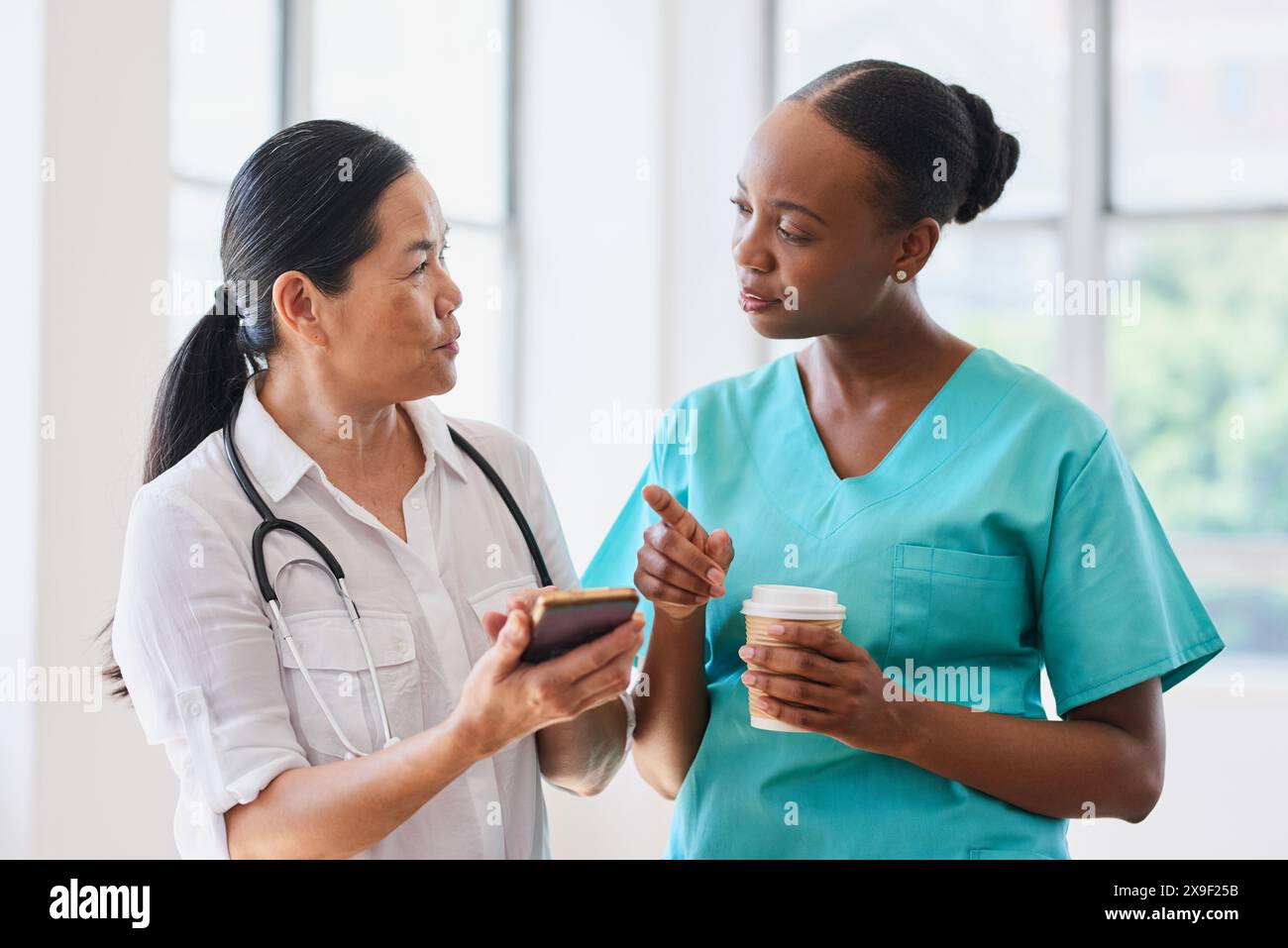Diverse Female Doctors Consulting in Hospital Setting with Coffee Stock ...