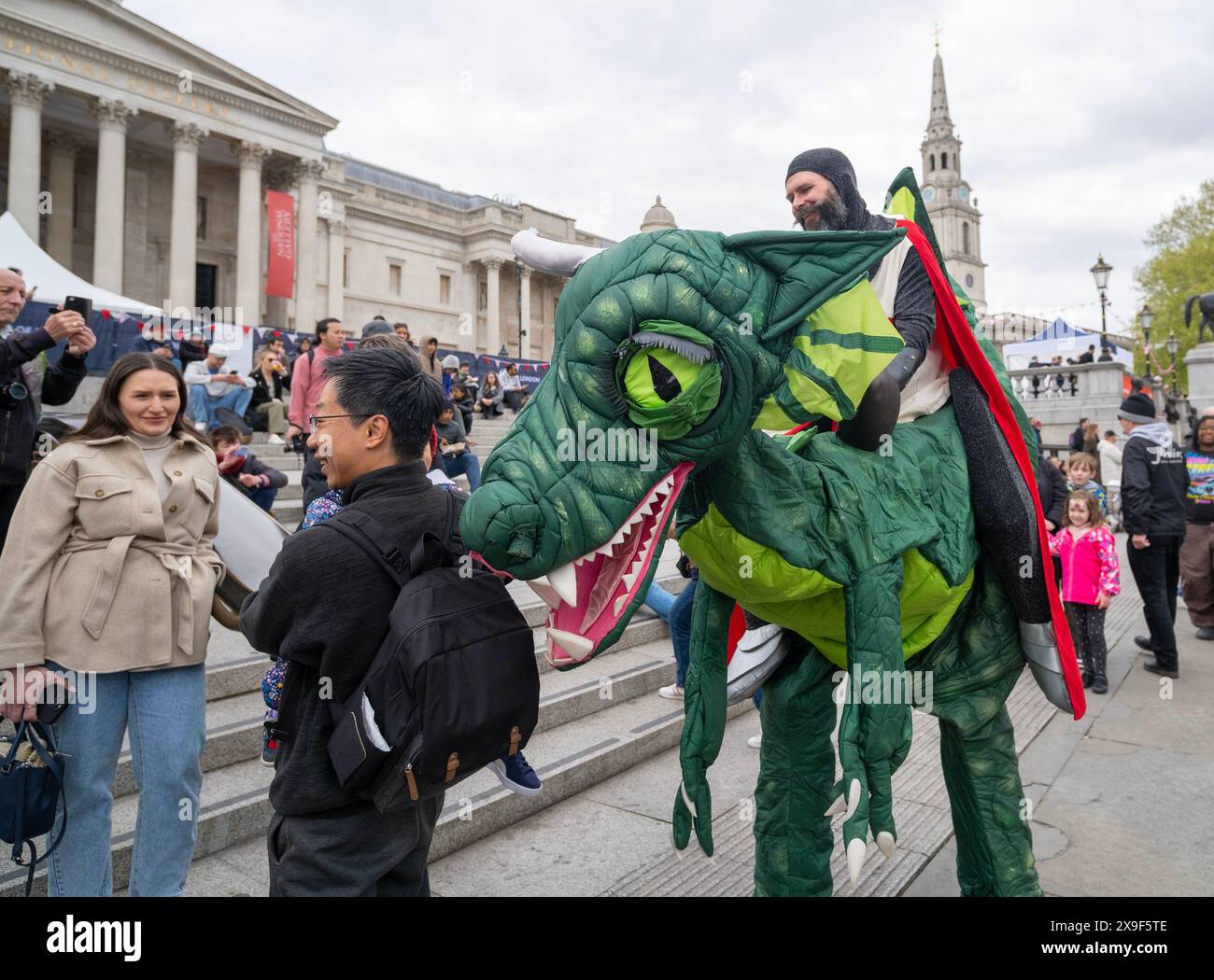 Performer dressed as St. George and riding a green dragon, meeting and ...