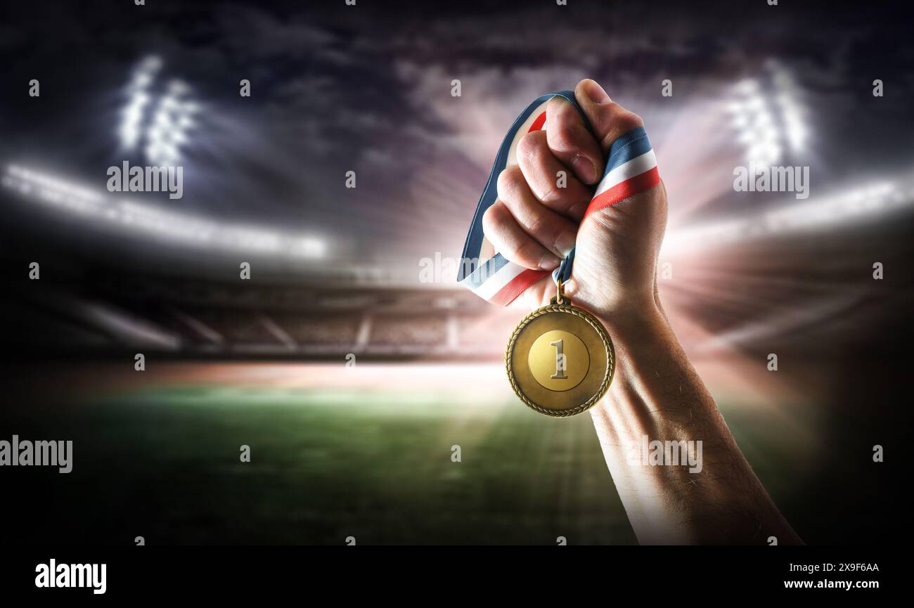 Hand showing gold medal with engraved number 1 and athletics stadium ...