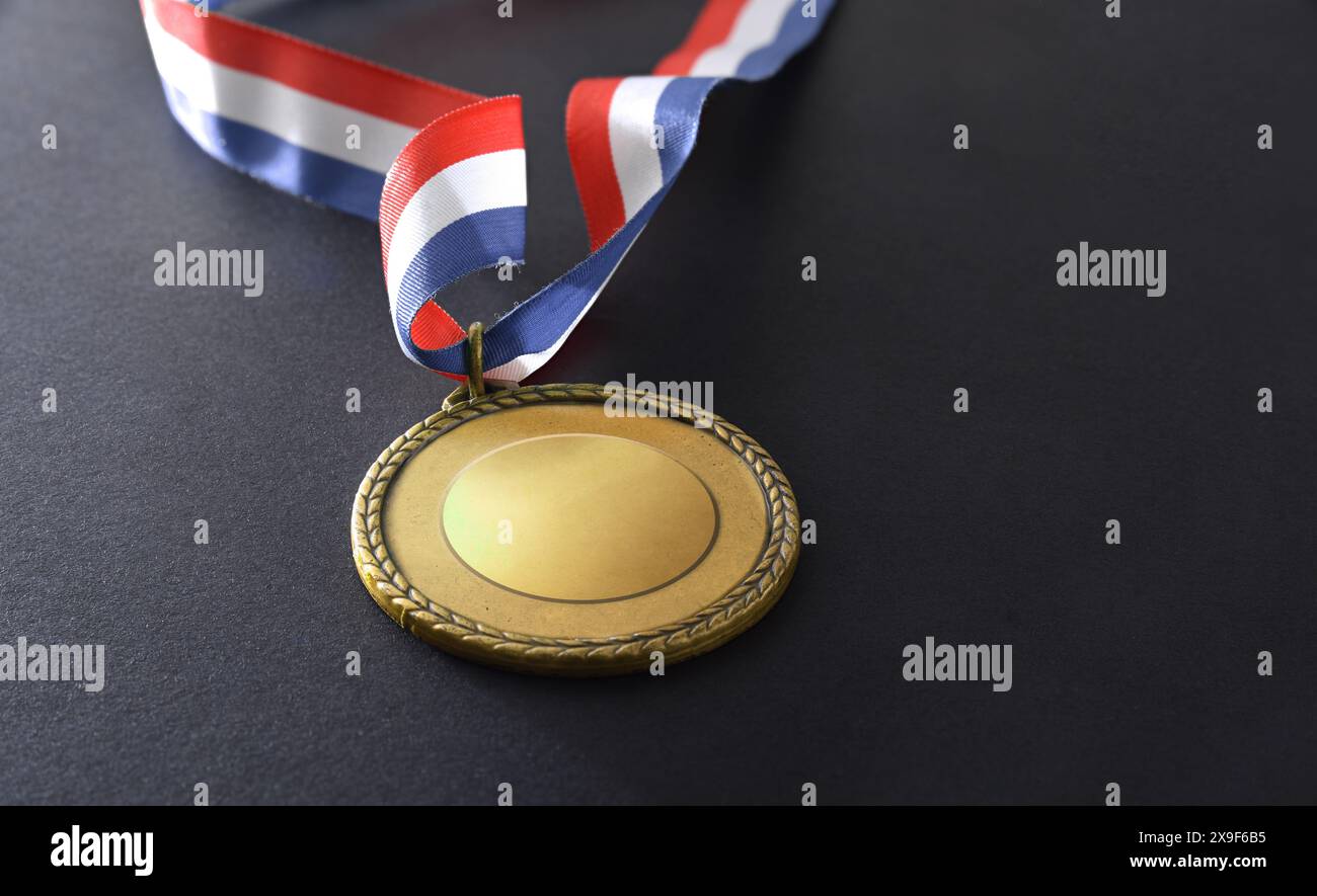 Golden metal medal with blue white and red colors isolated on black ...