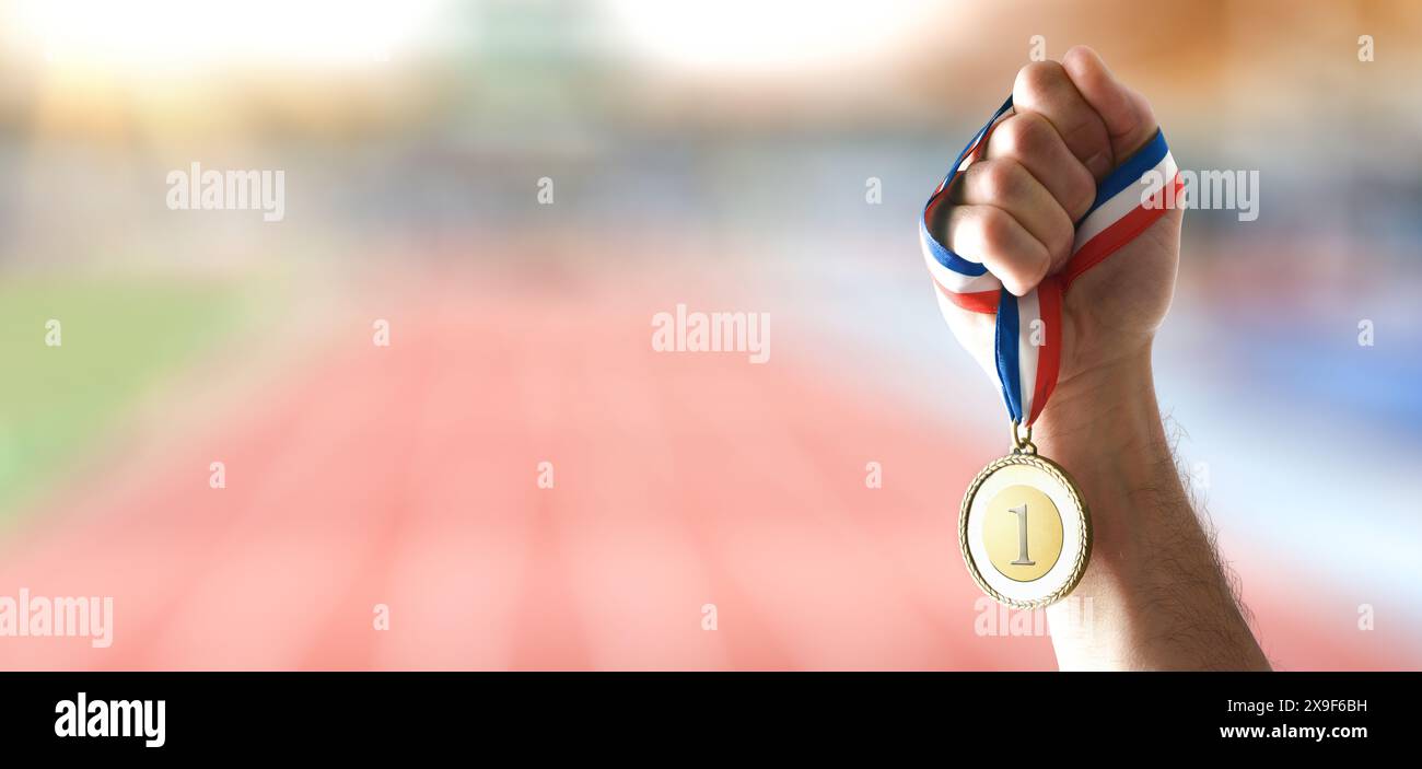 Hand showing gold medal with engraved number 1 and athletics stadium ...