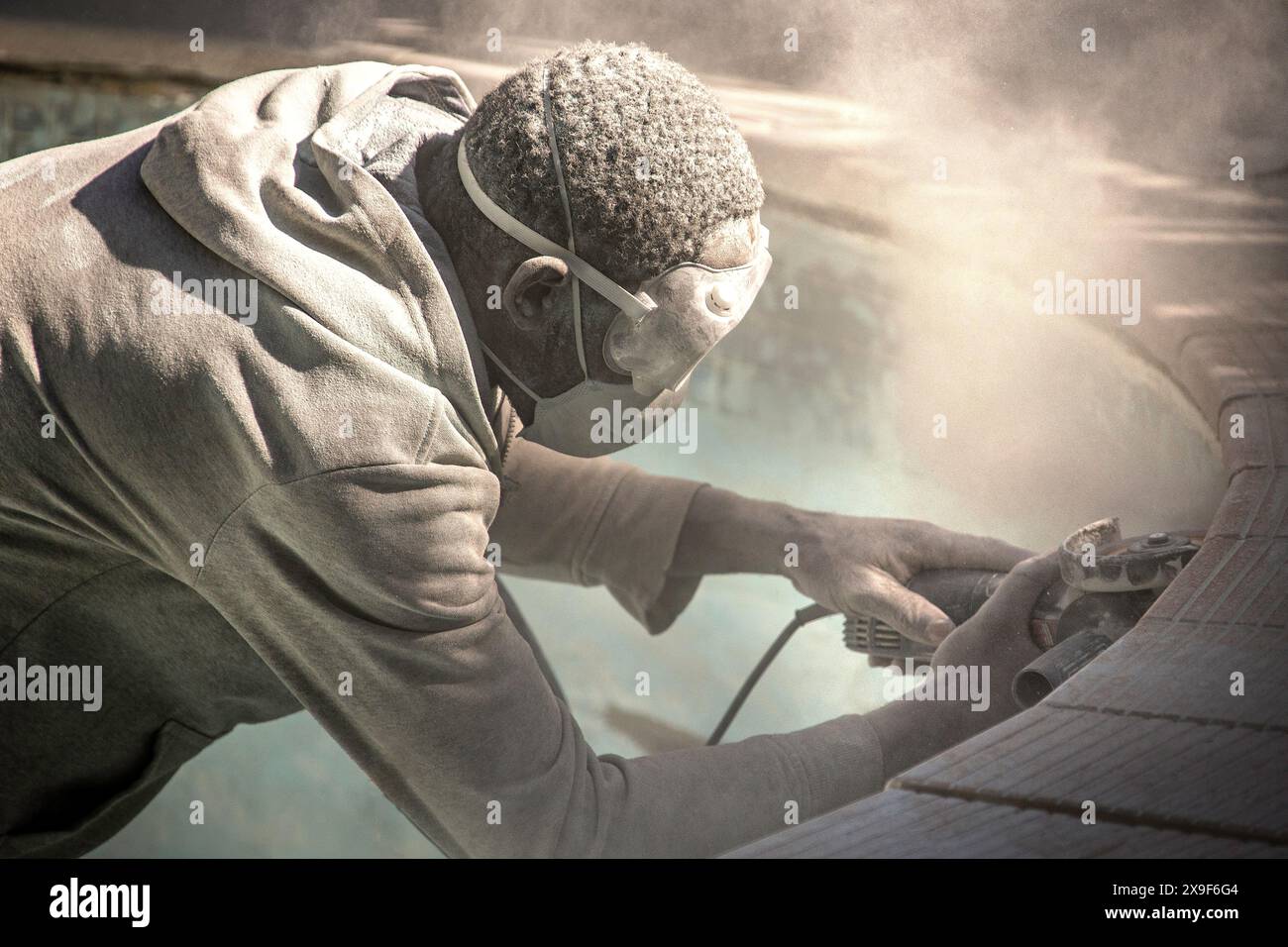 A workman grinding out the lip of old fibreglass and making dust Stock ...