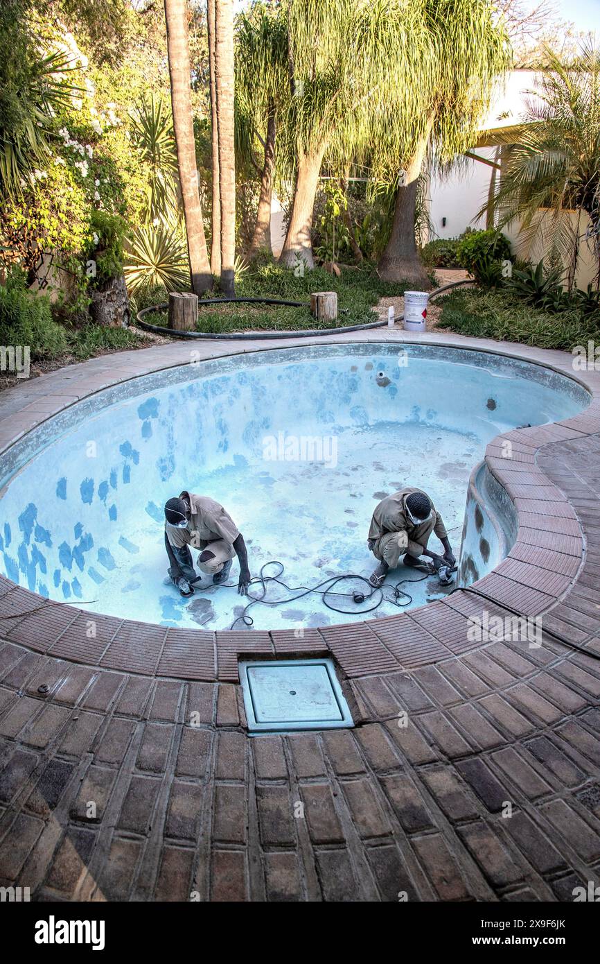 Two crouching workmen griniding out the bubbles in an old fibreglass ...