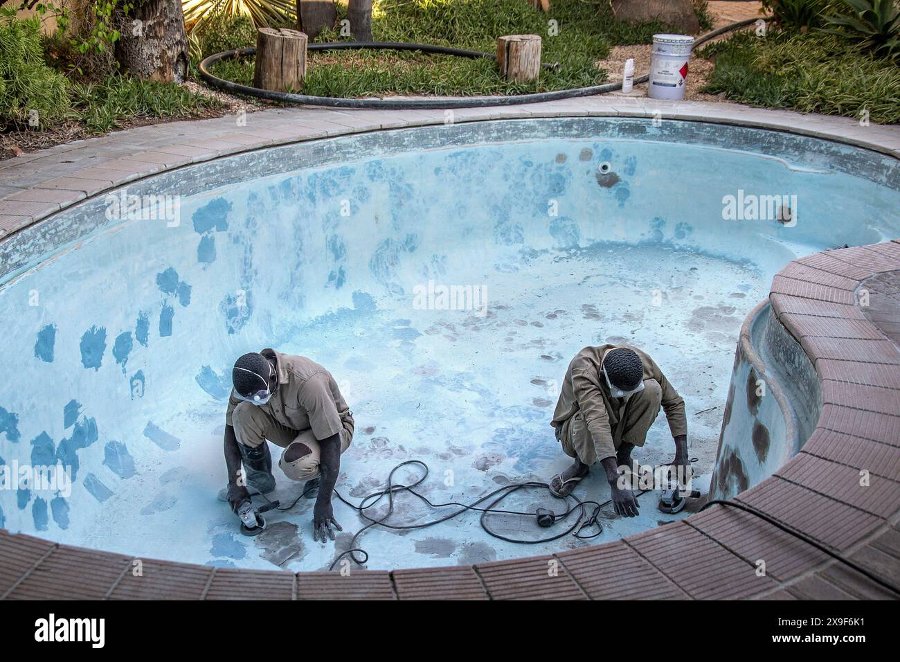 Two crouching workmen griniding out the bubbles in an old fibreglass ...