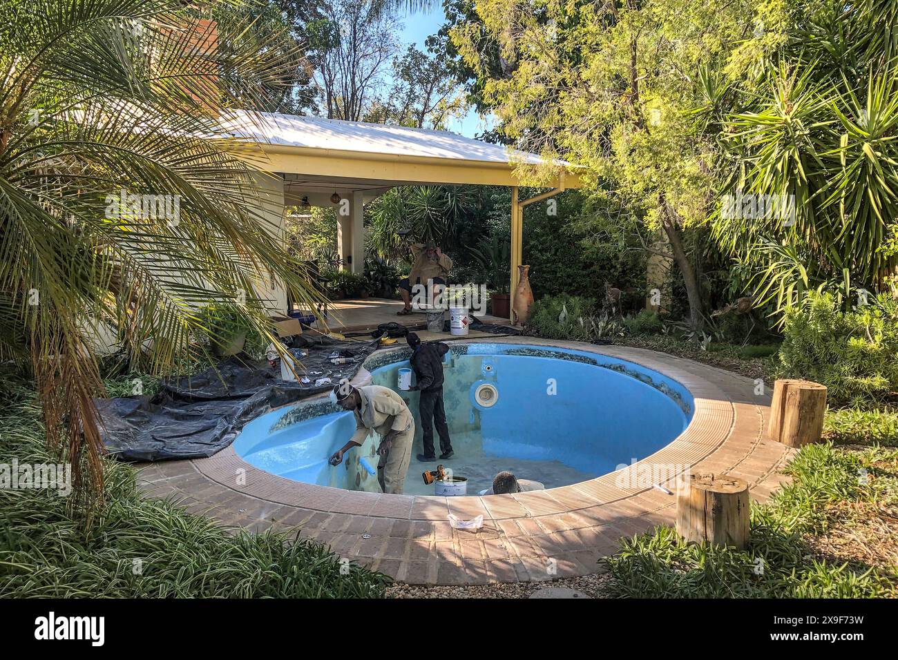 Workman using rollers and a paintbrush to apply fibreglass gel coat ...