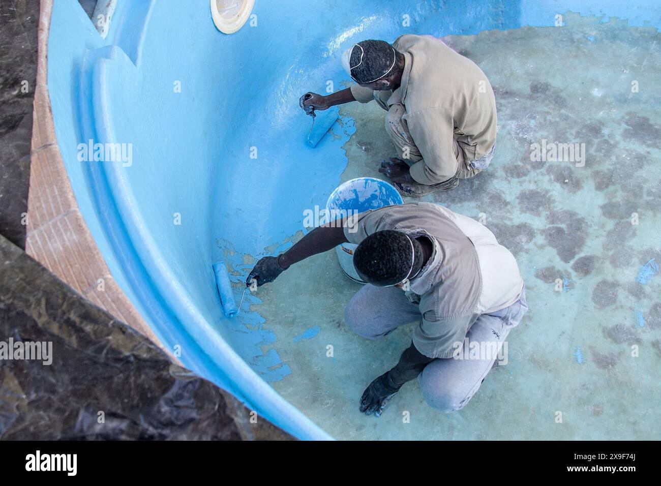 Workmen using rollers to apply fibreglass gel coat paint to an old ...