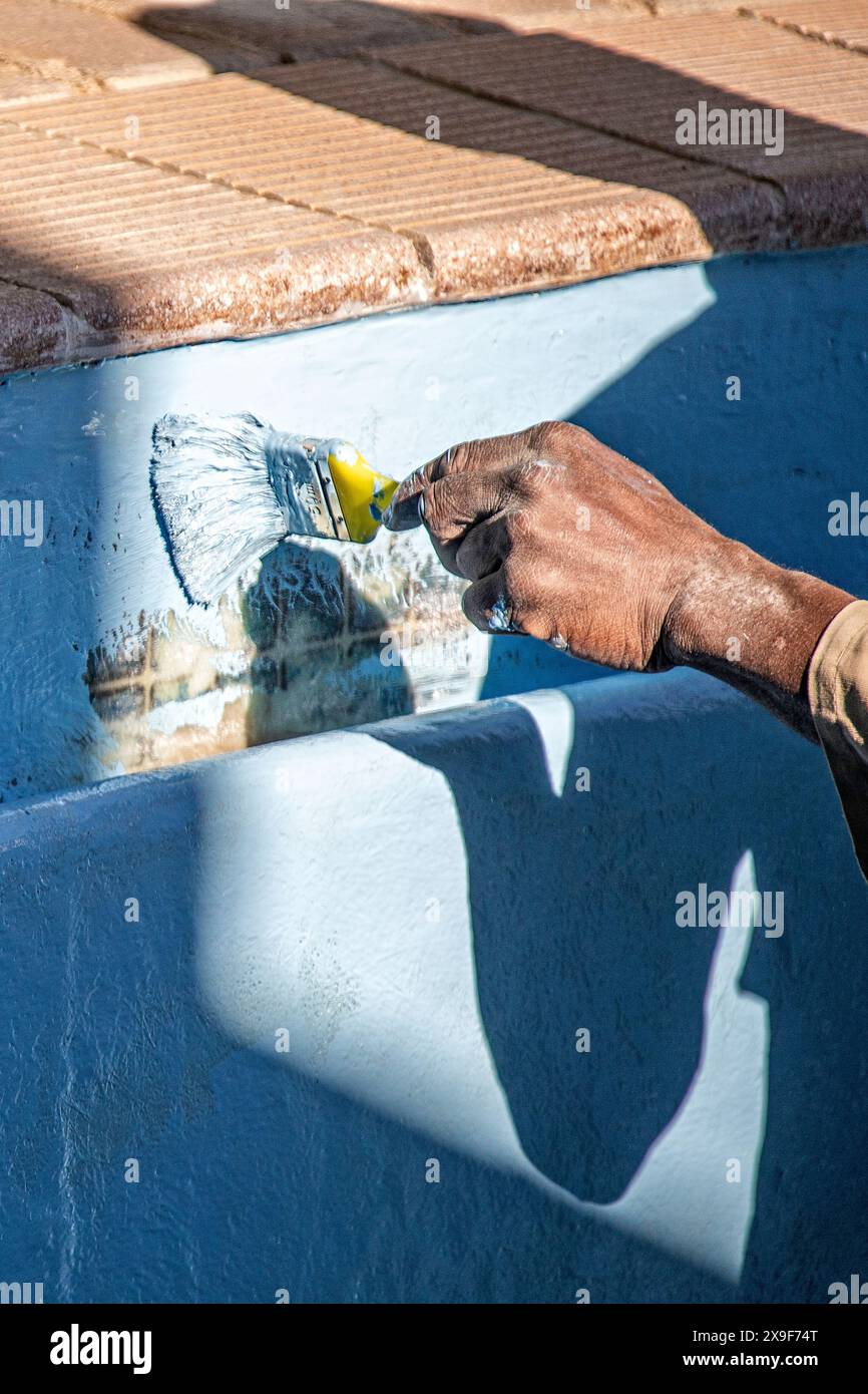 Workman using a paintbrush to apply fibreglass gel coat paint to an old ...