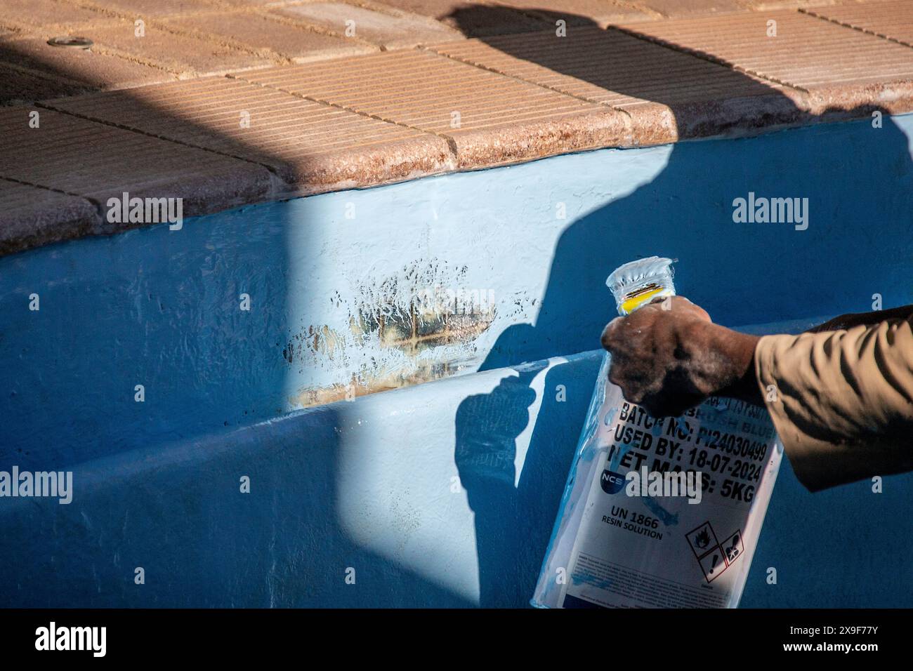 Workman using a paintbrush to apply fibreglass gel coat paint to an old ...
