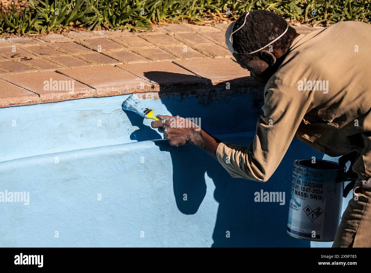 Workman using a paintbrush to apply fibreglass gel coat paint to an old ...