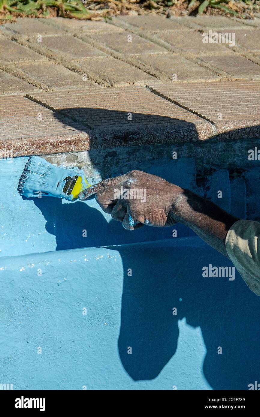 Workman using a paintbrush to apply fibreglass gel coat paint to an old ...