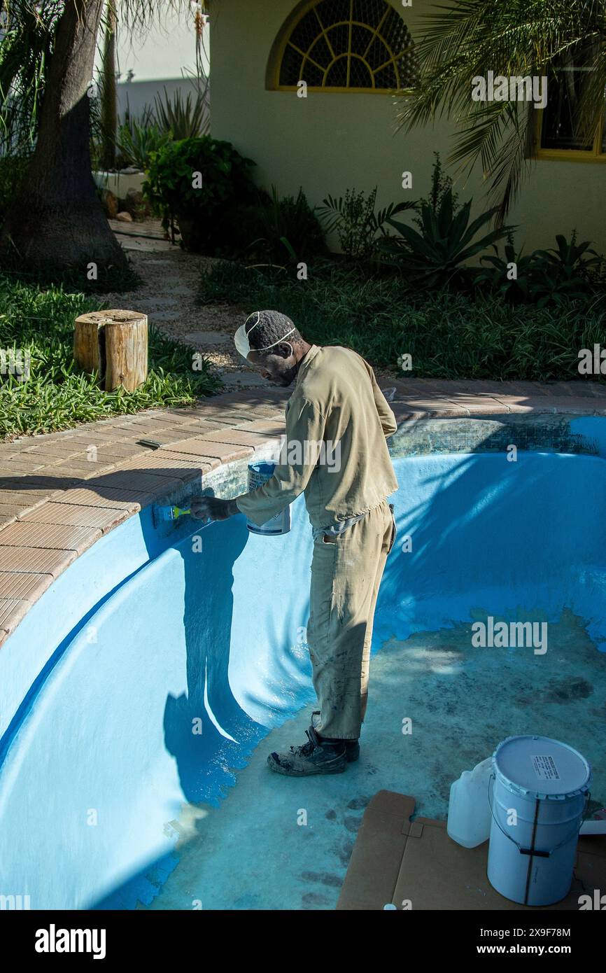 Workman using a paintbrush to apply fibreglass gel coat paint to an old ...