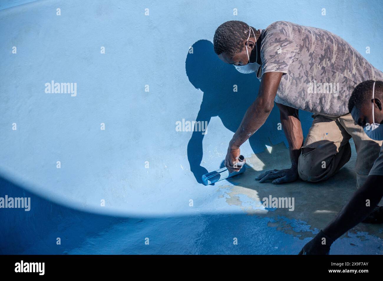 Workmen using rollers to apply fibreglass gel coat paint to an old ...