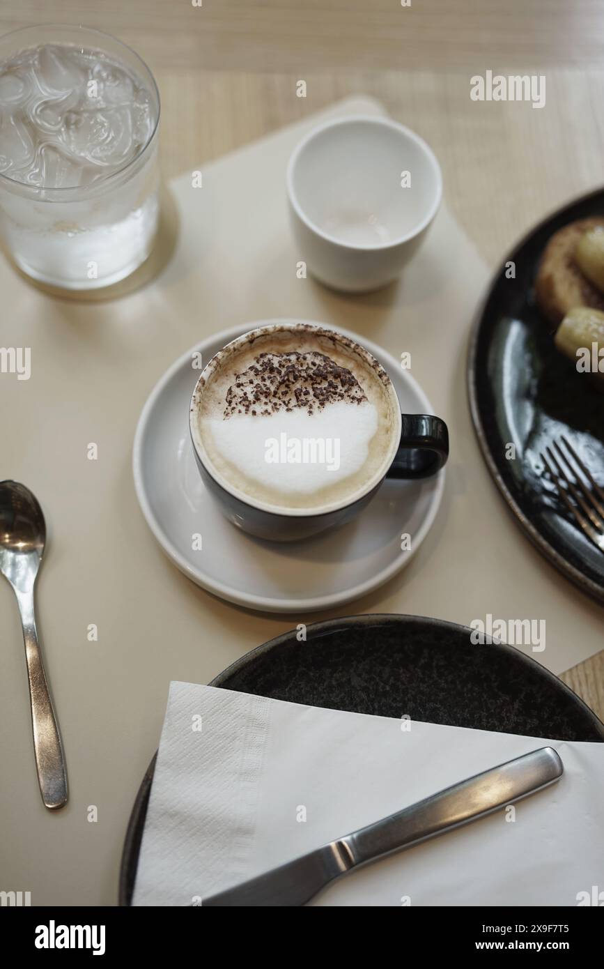Frothy cappuccino coffee with dessert glass of water breakfast meal ...