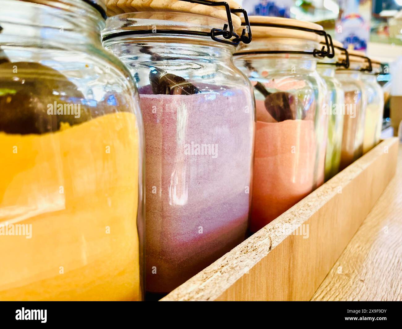 Close-up of glass jars on a shelf filled with assorted flavours of ...