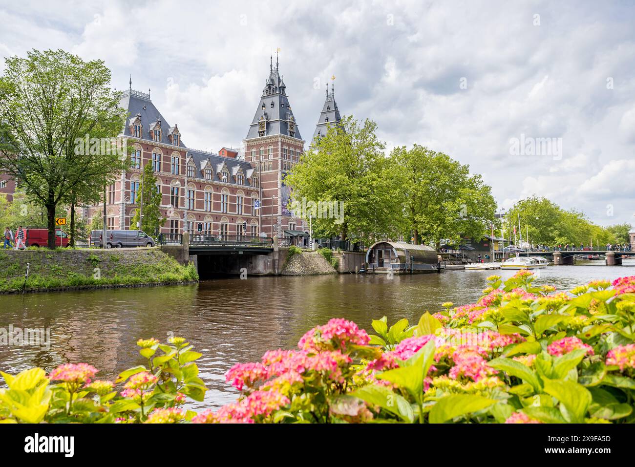 View to the Rijksmuseum across pretty pink flowers and a waterway ...