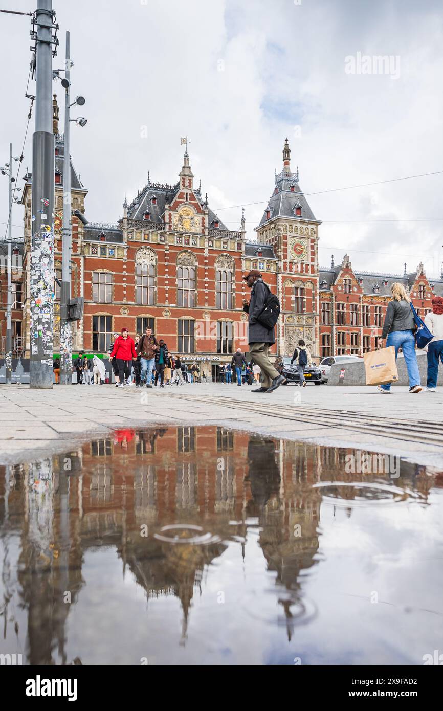 Rain begins again as the front of Amsterdam Centraal reflects in a ...