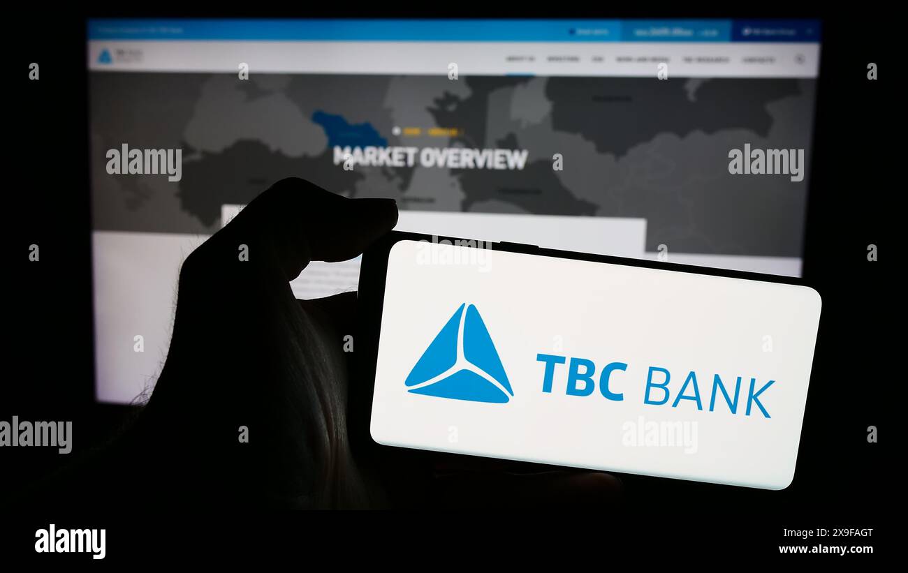 Person holding smartphone with logo of Georgian financial services company TBC Bank Group plc in ...