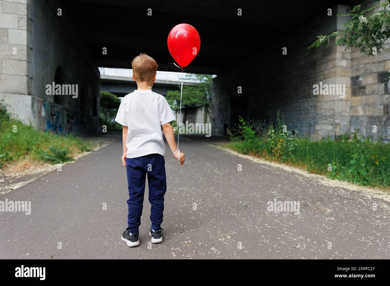 Back view little cute kid boy hold red balloon stand in front of dark ...