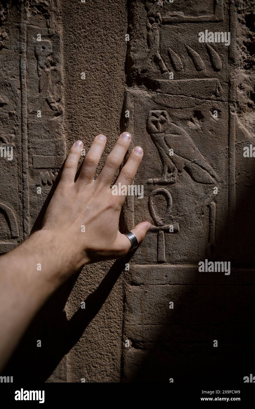 Close-up of a man touching Egyptian Hieroglyphs on a column, Karnak ...