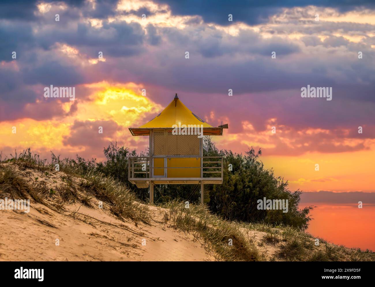 Dramatic sunset over a Lifeguard hut in sand dunes on a beach ...