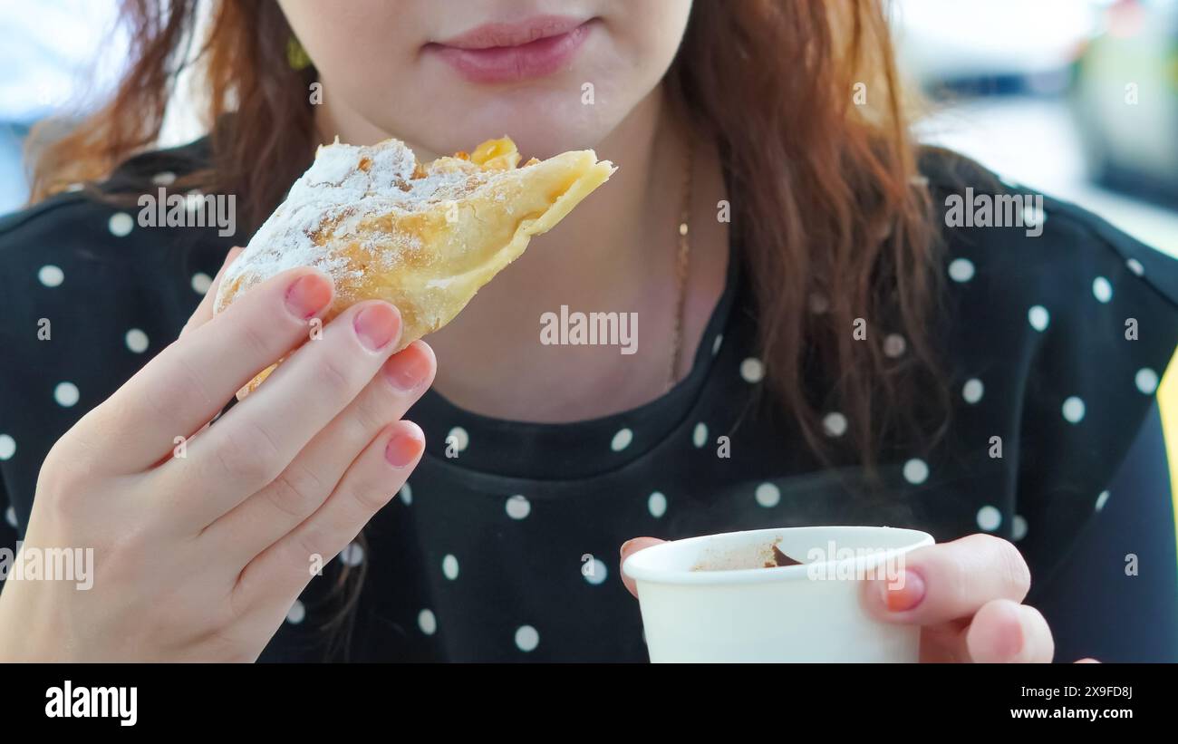 close up of woman drinking coffee from paper cup and eating bakery ...