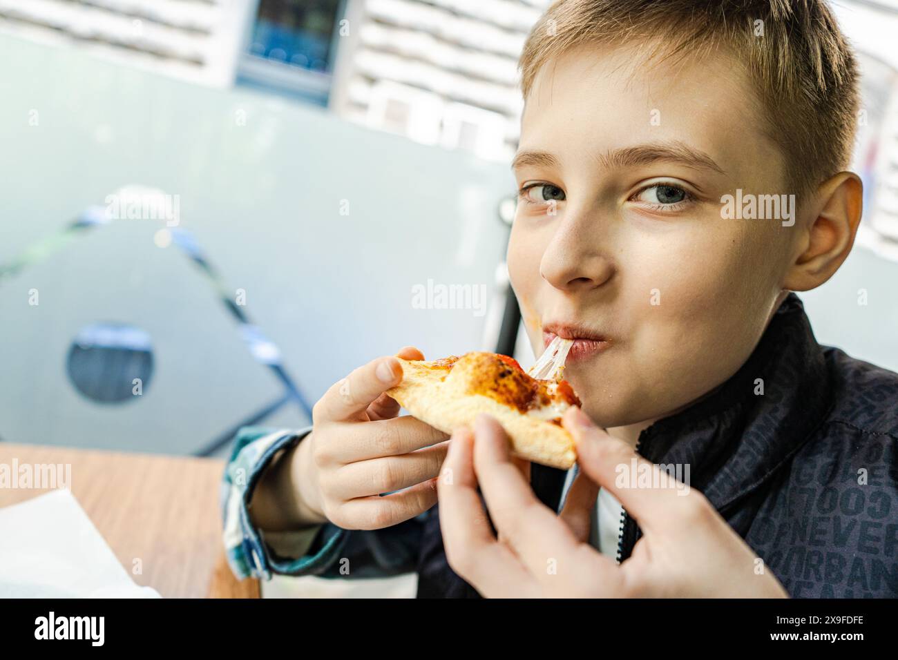 Portrait of a smiling boy eating a pepperoni, olive and jalapeno pizza ...